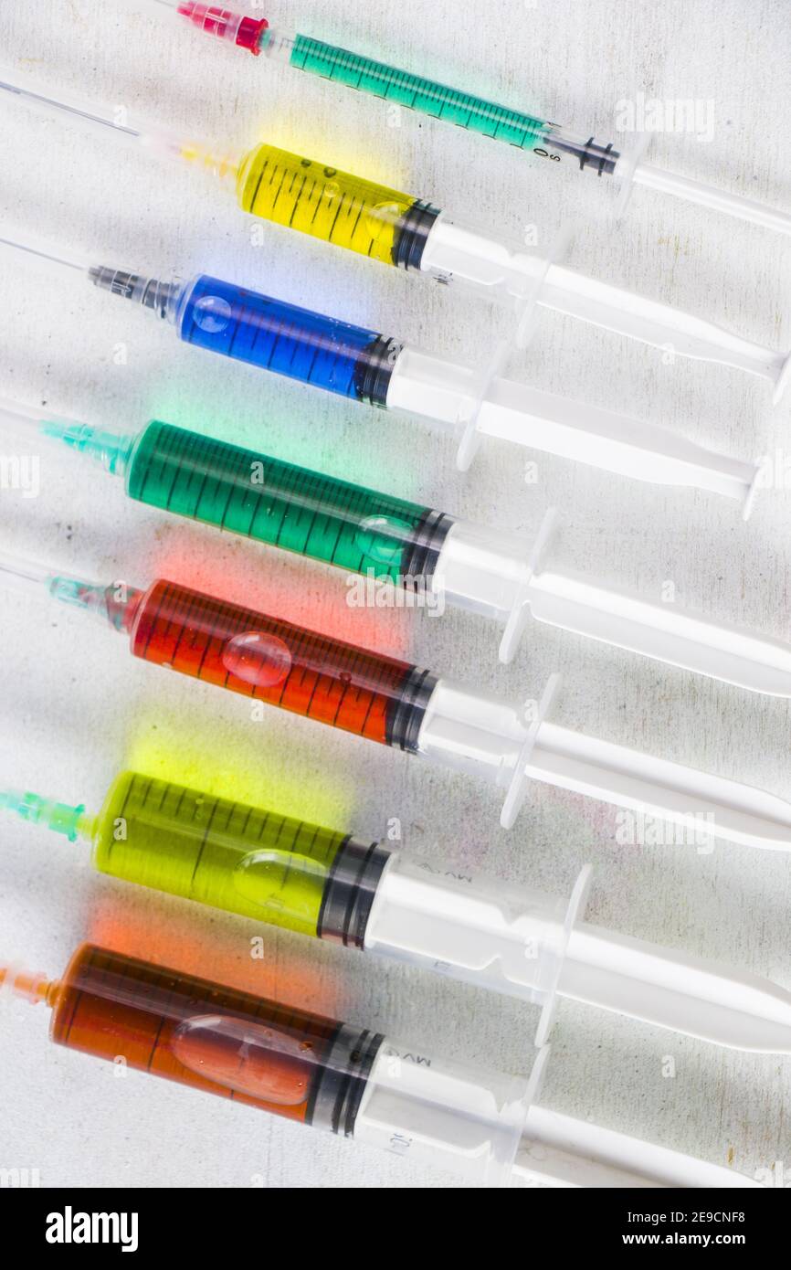 Vertical shot of syringe needles with colorful chemicals on the table ...