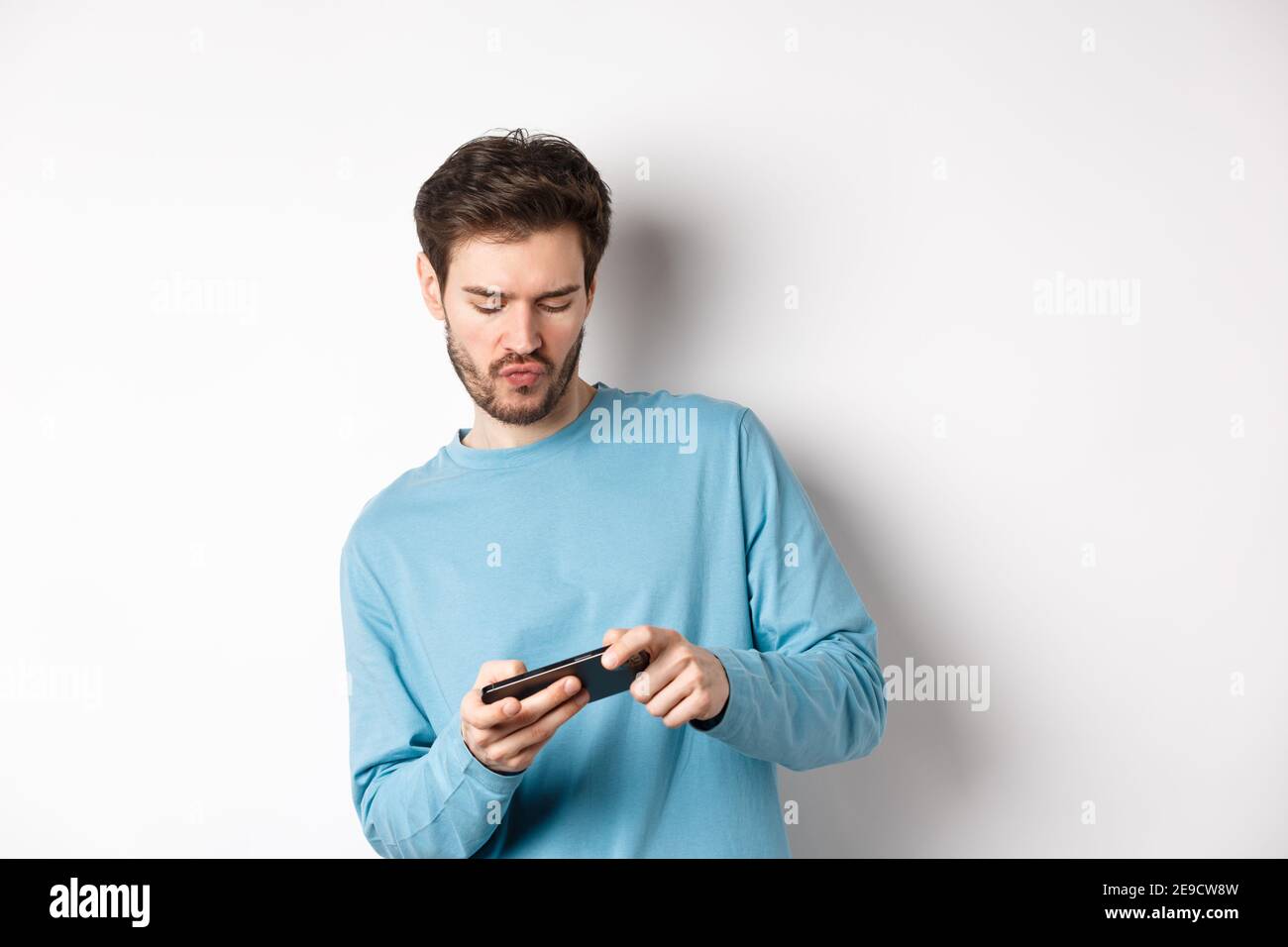 Young man playing video games on smartphone, tilt body and tap mobile ...