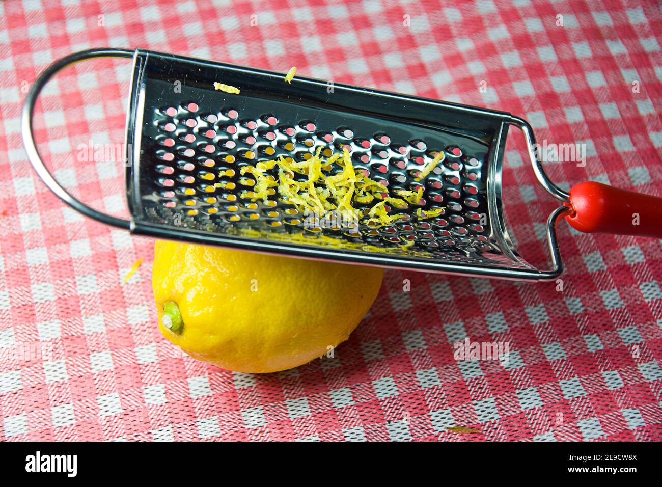 Closeup of a grating fresh lemon on a red checkered surface Stock Photo ...