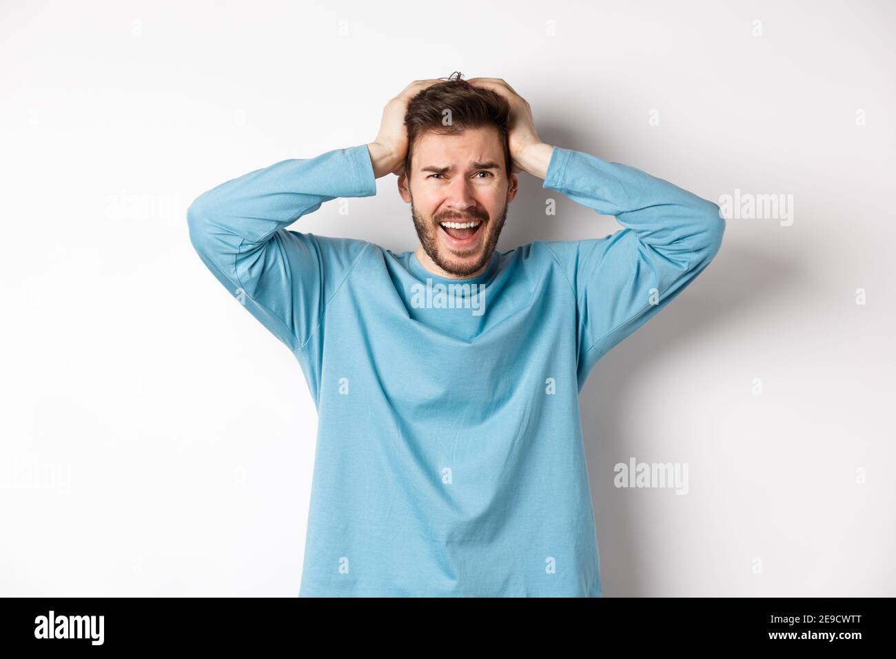 Frustrated young man screaming in panic, standing anxious on white ...