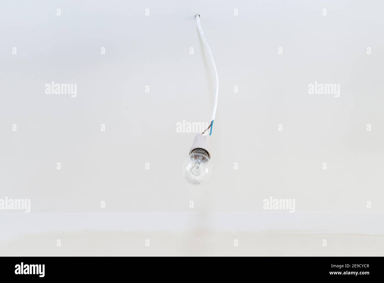 Light bulb hanging on a cable protruding from the wall with a ceramic ...