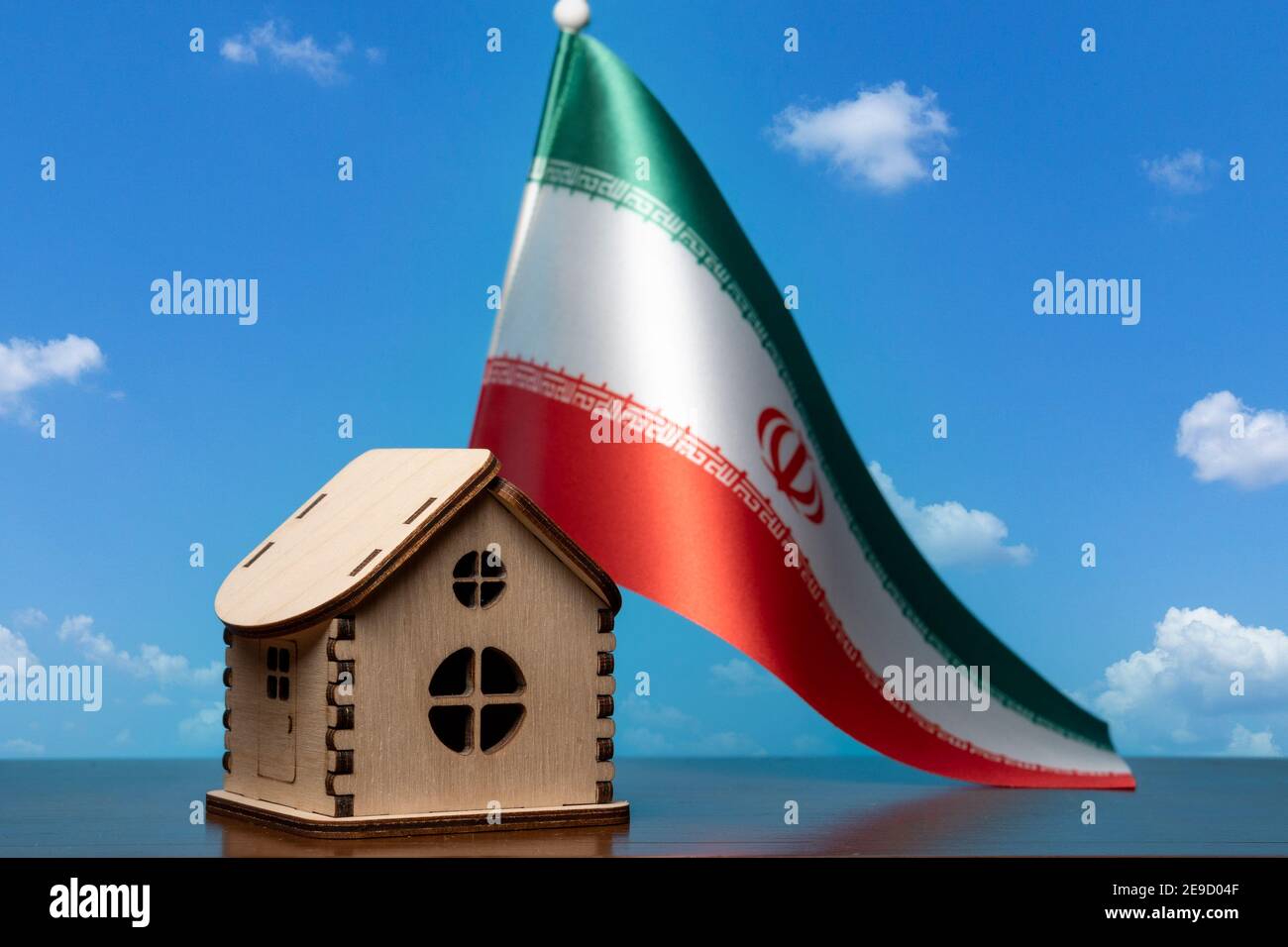 Small wooden house and Iran flag, sky on background. Real estate ...
