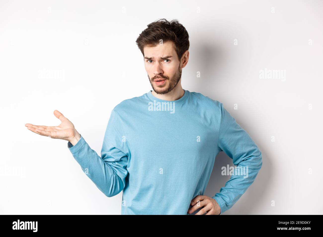 So what. Confused young man raising hand and looking skeptical at ...