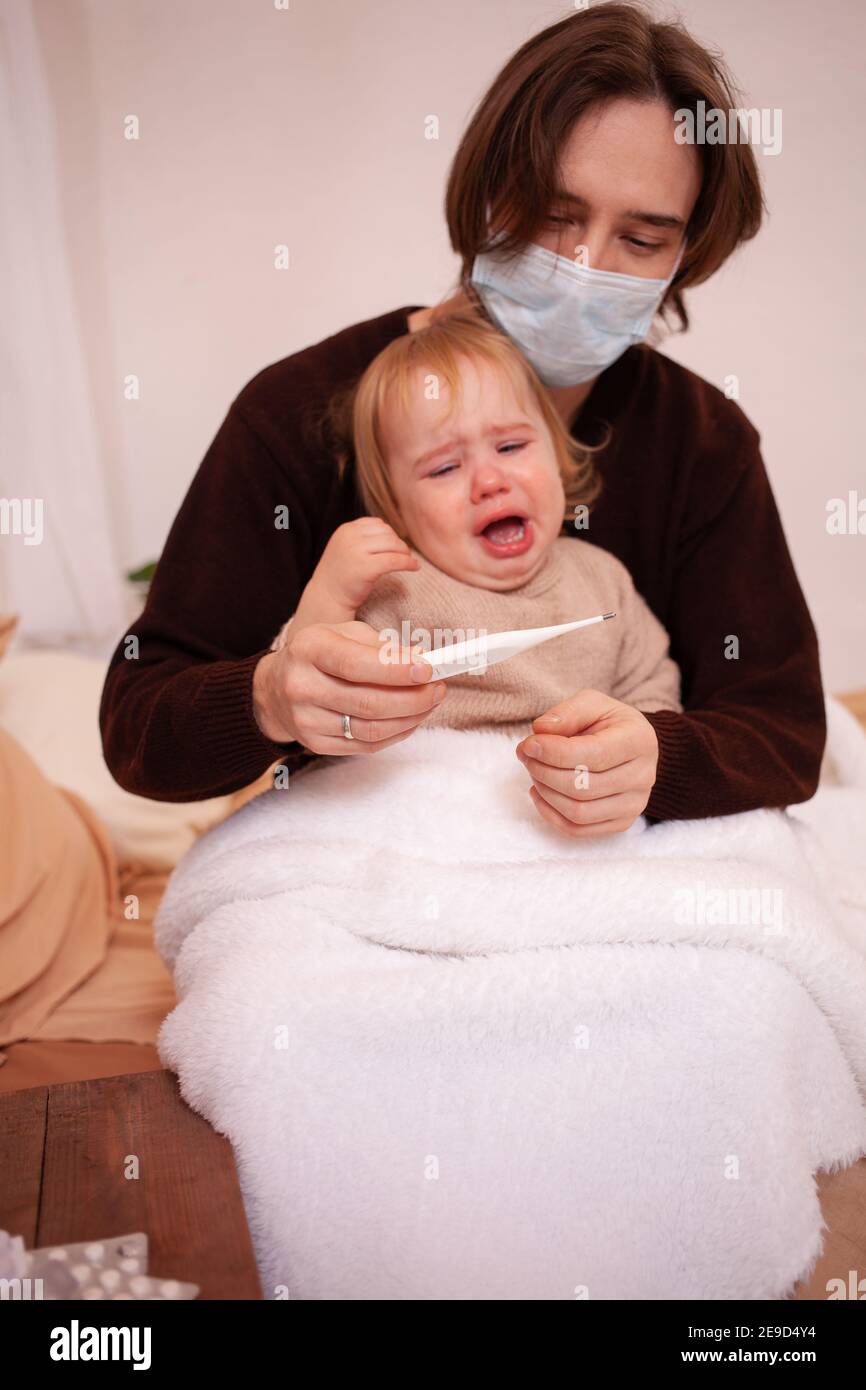 The child at home is sick, screaming and suffering. Dad in a mask ...