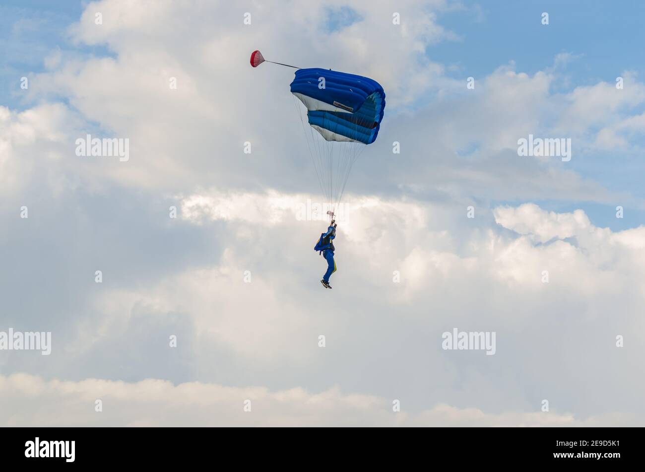 blue parachute jumpers in the sky with clouds Stock Photo - Alamy