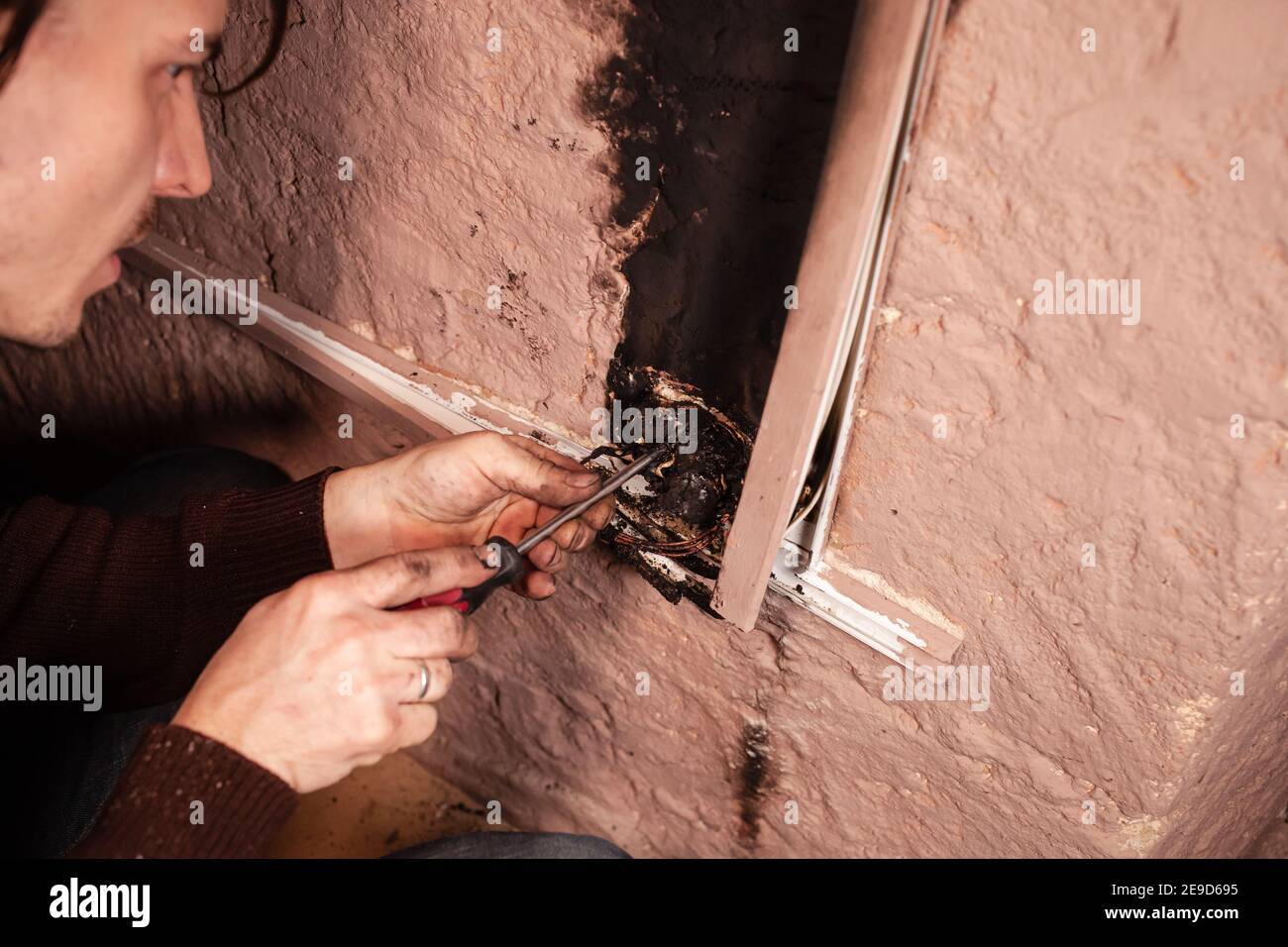 A man fixes a burnt socket. Short circuit, burnt wires. traces of smoke ...