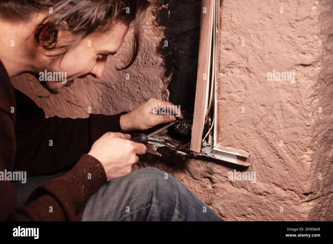 A man fixes a burnt socket. Short circuit, burnt wires. traces of smoke ...
