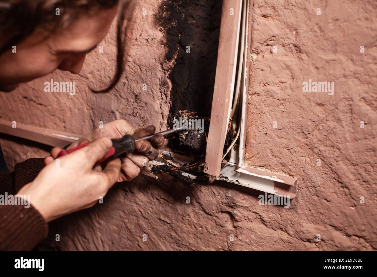 A man fixes a burnt socket. Short circuit, burnt wires. traces of smoke ...