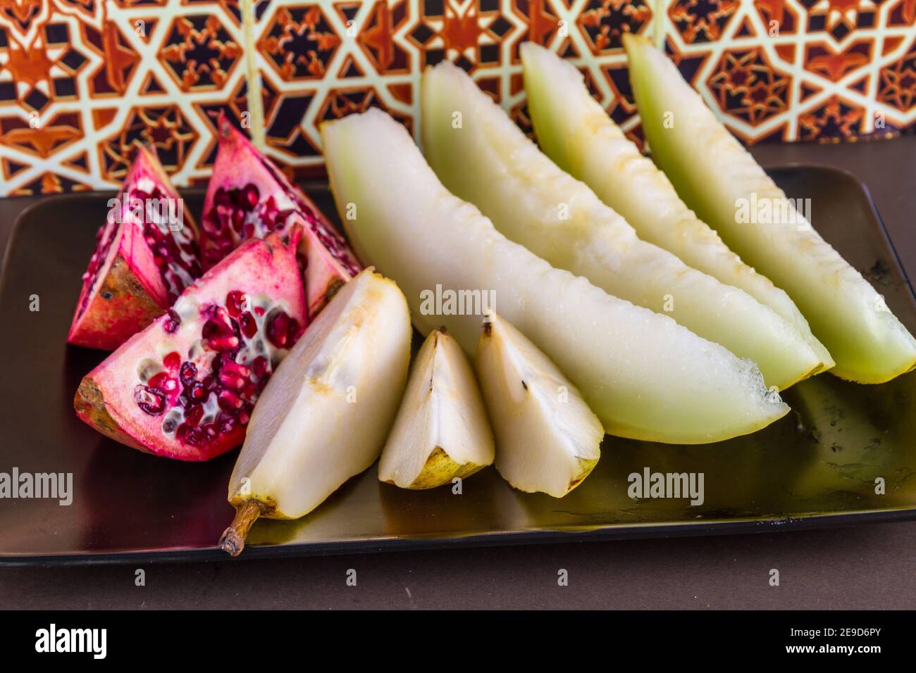 pomegranate melon and pear sliced and arranged on plate. Moorish tile ...