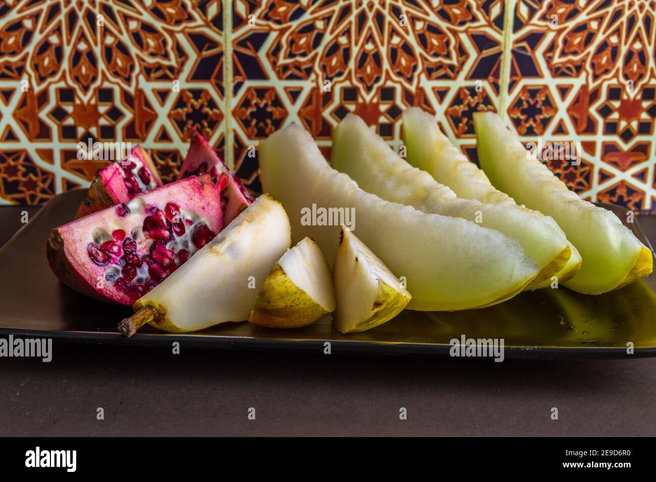 pomegranate melon and pear sliced and arranged on plate landscape ...