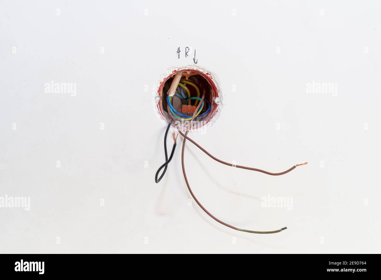 Electric cables sticking out of an orange box placed in the wall of the ...