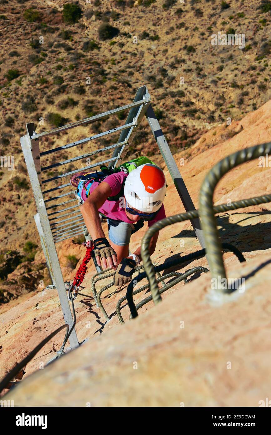 female hiker on a rock wall, hard via ferrata of Redovan, Spain ...