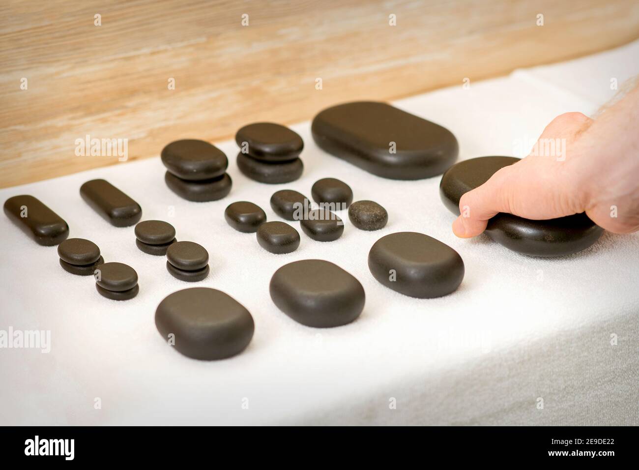 Hand of massage therapist taking massage stones from the table before ...