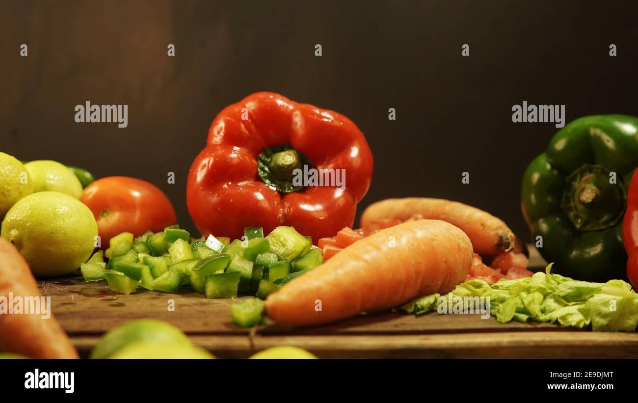 Red paprika, carrot, and other chopped vegetables on a brown background ...