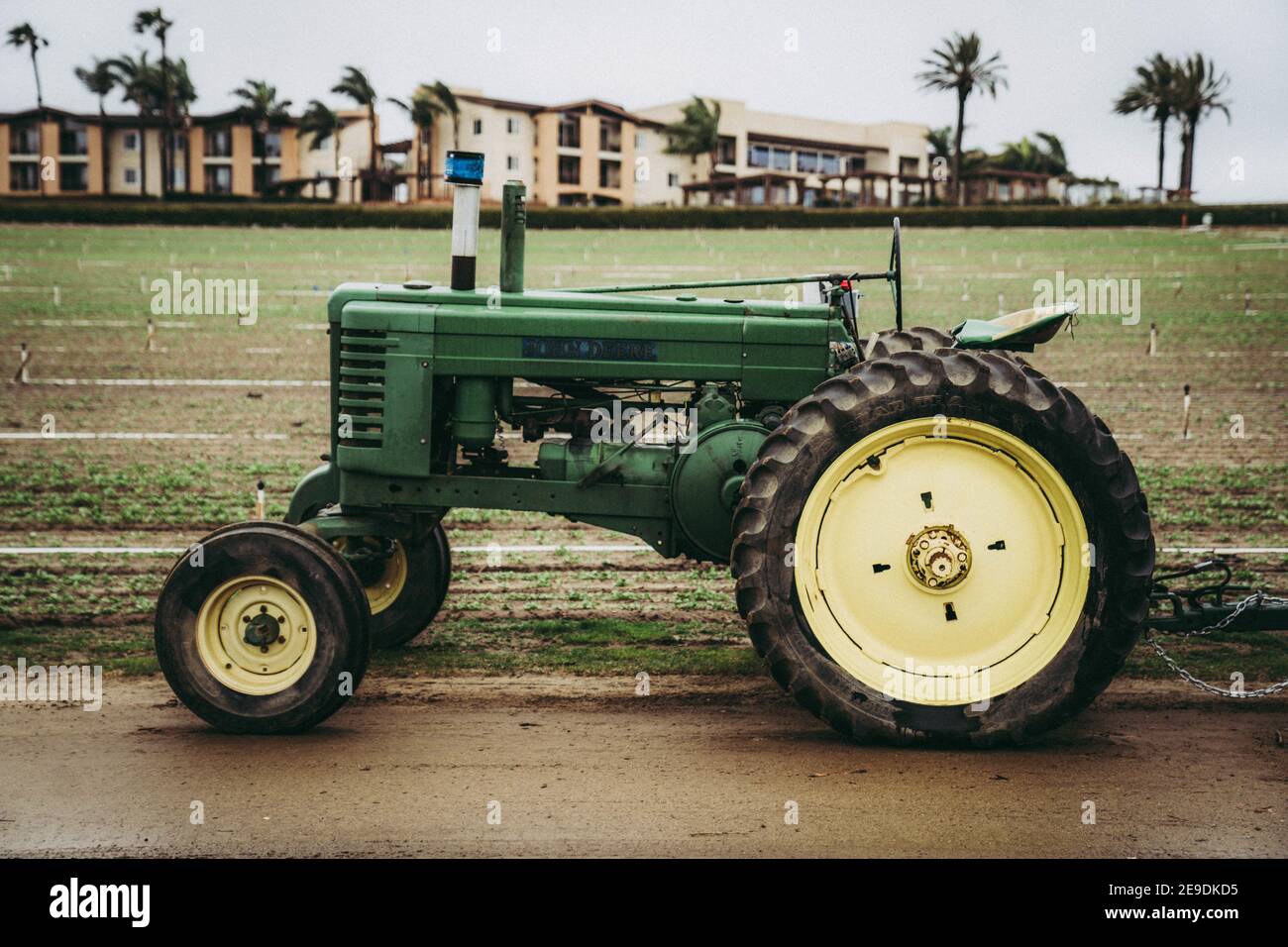 Old clear tractor painted in green and residential buildings Stock ...