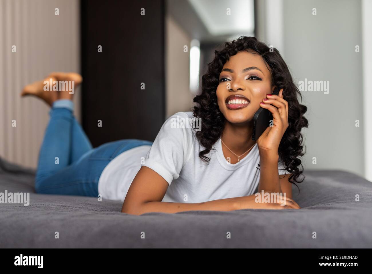 cheerful african woman making phone call in bedroom Stock Photo - Alamy