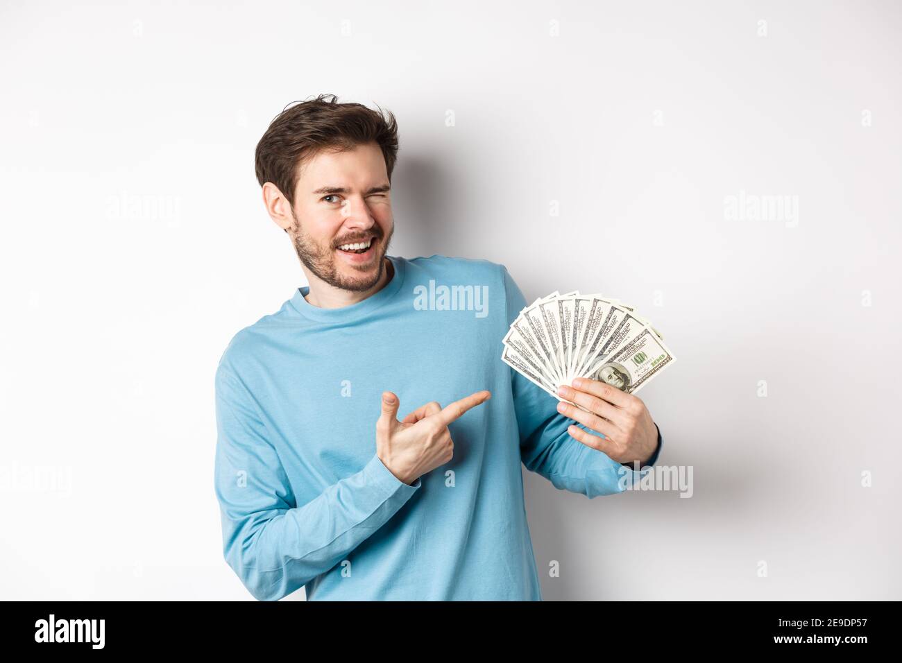 Handsome rich guy winking at camera, showing income, pointing finger at ...