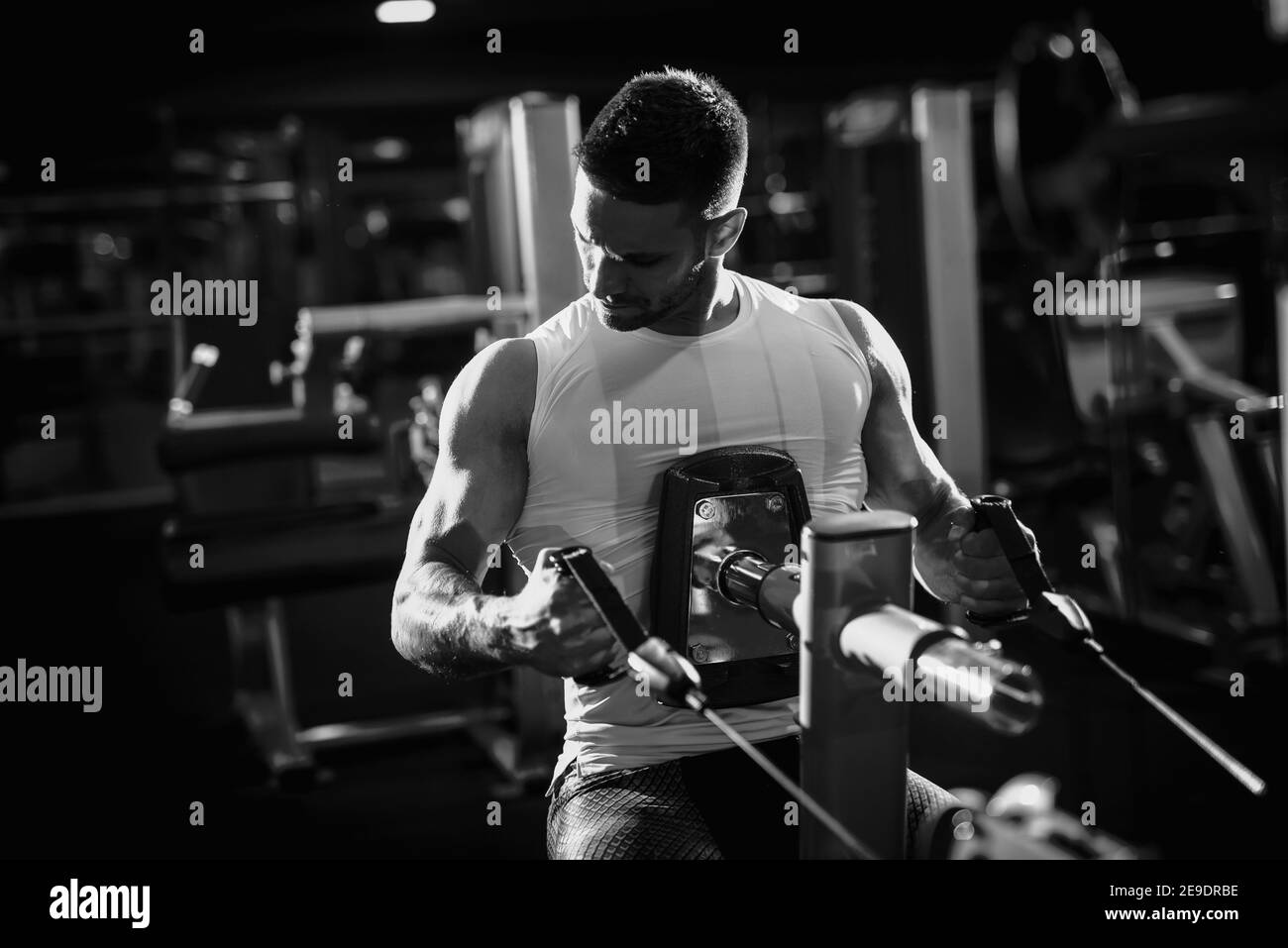 Portrait of a muscular man doing exercises in a gym. Backlight, black ...