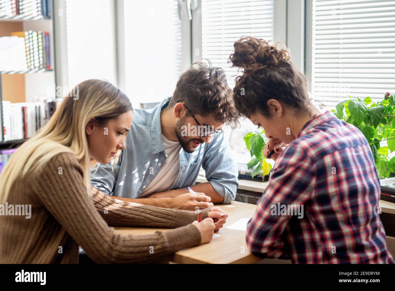 Small group of student sitting and doing homework. Library interior ...