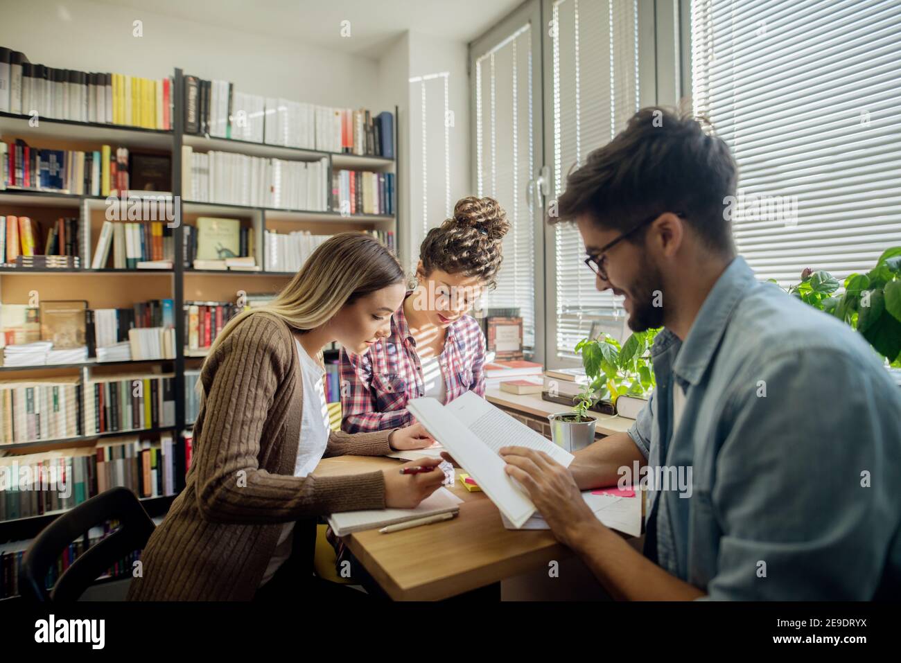 Students sitting in library and studying for exams. In background ...