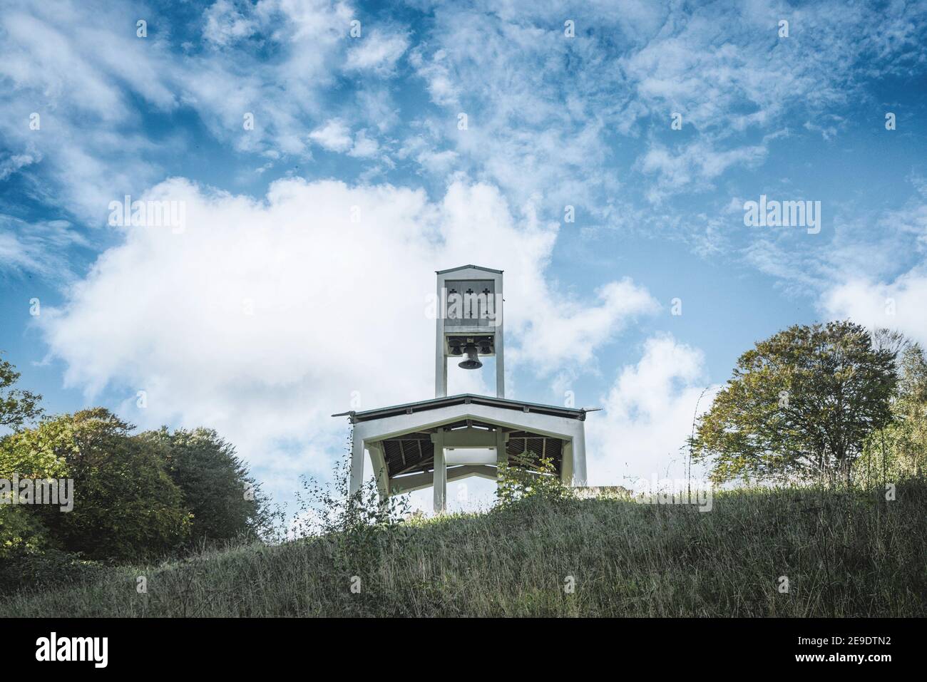 Holy bell tower with religious symbols in green nature under a blue ...