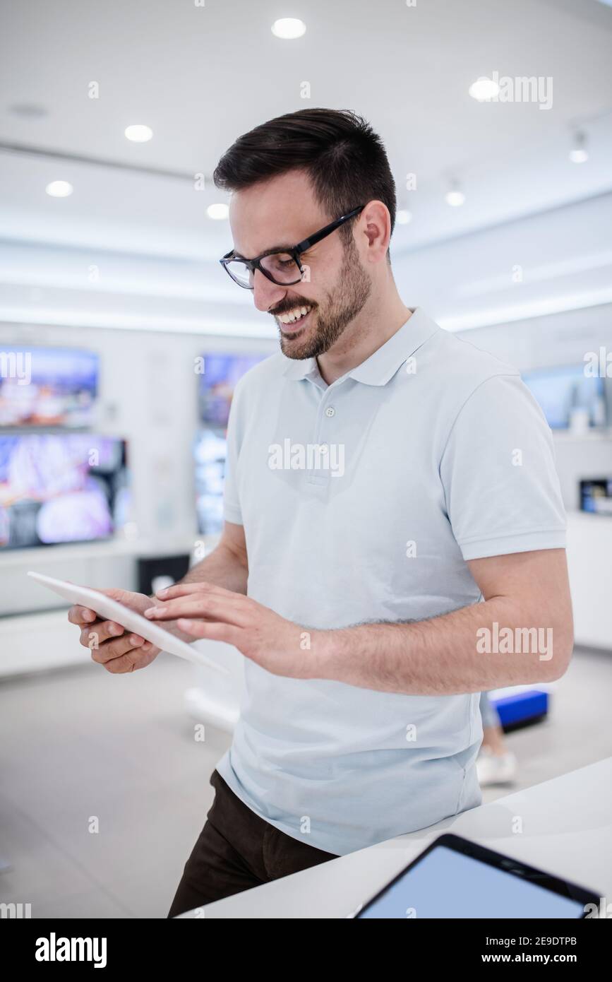 Man standing in tech store and trying out tablet Stock Photo - Alamy