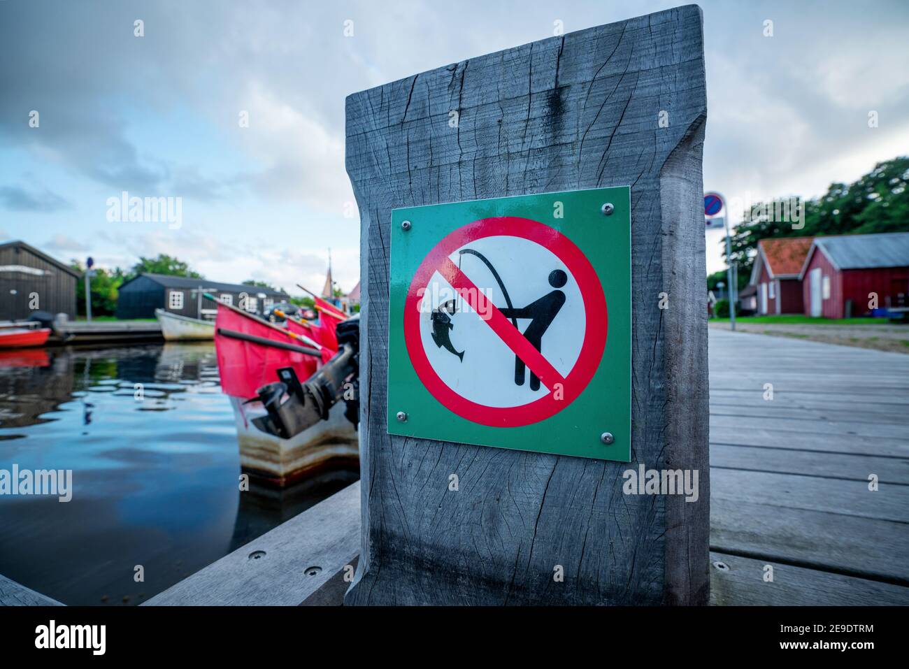 Fishing prohibited sign on a wooden pier at a marine harbor in cloudy ...