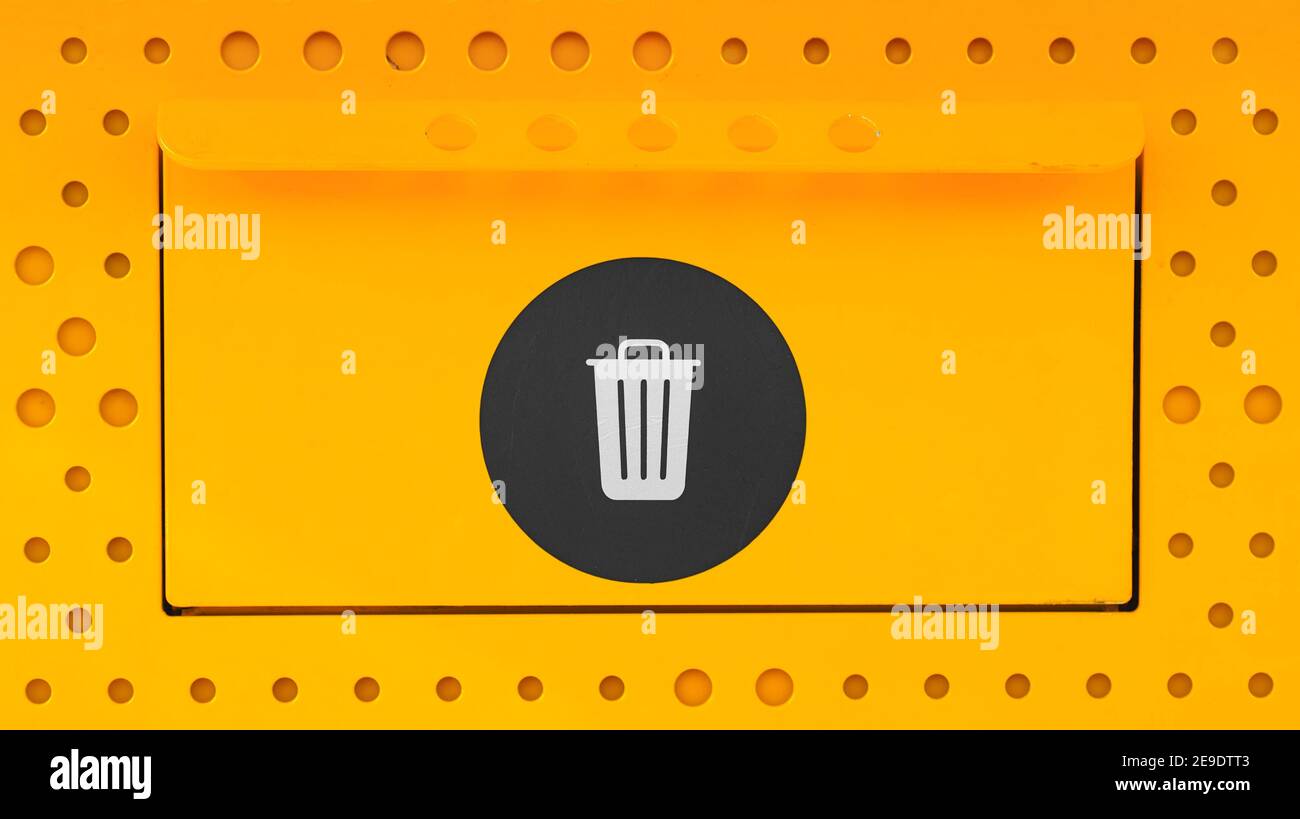 Yellow trash can close-up with a black sticker on the lit. Garbage bin ...