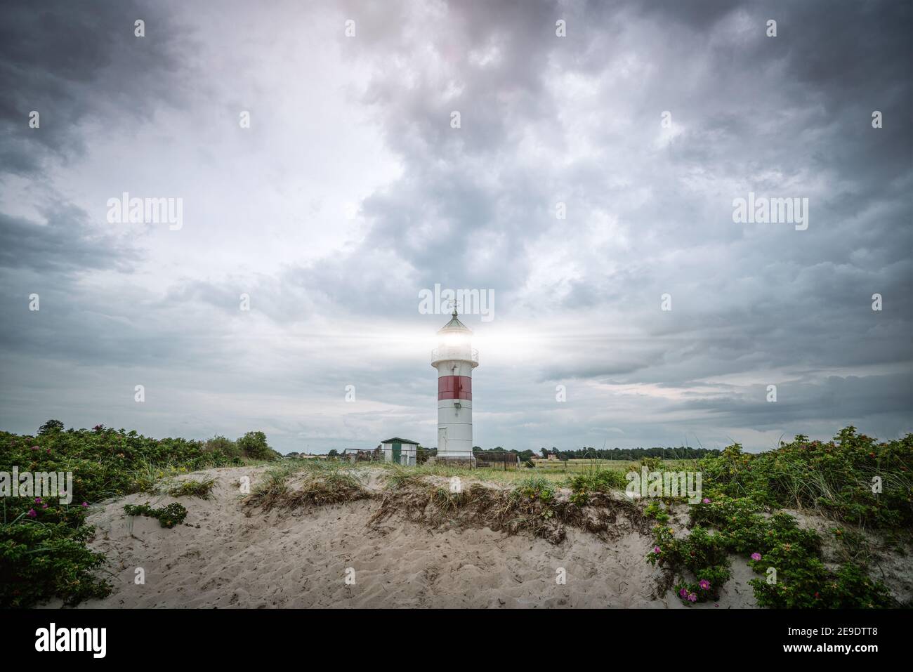 Lighthouse in cloudy weather in the afternoon on a beach with green ...