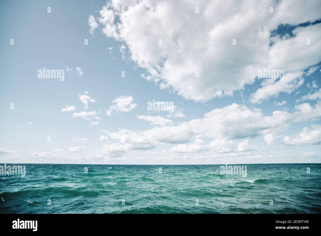 Turquoise water in a cold nordic sea under a blue sky with white clouds ...