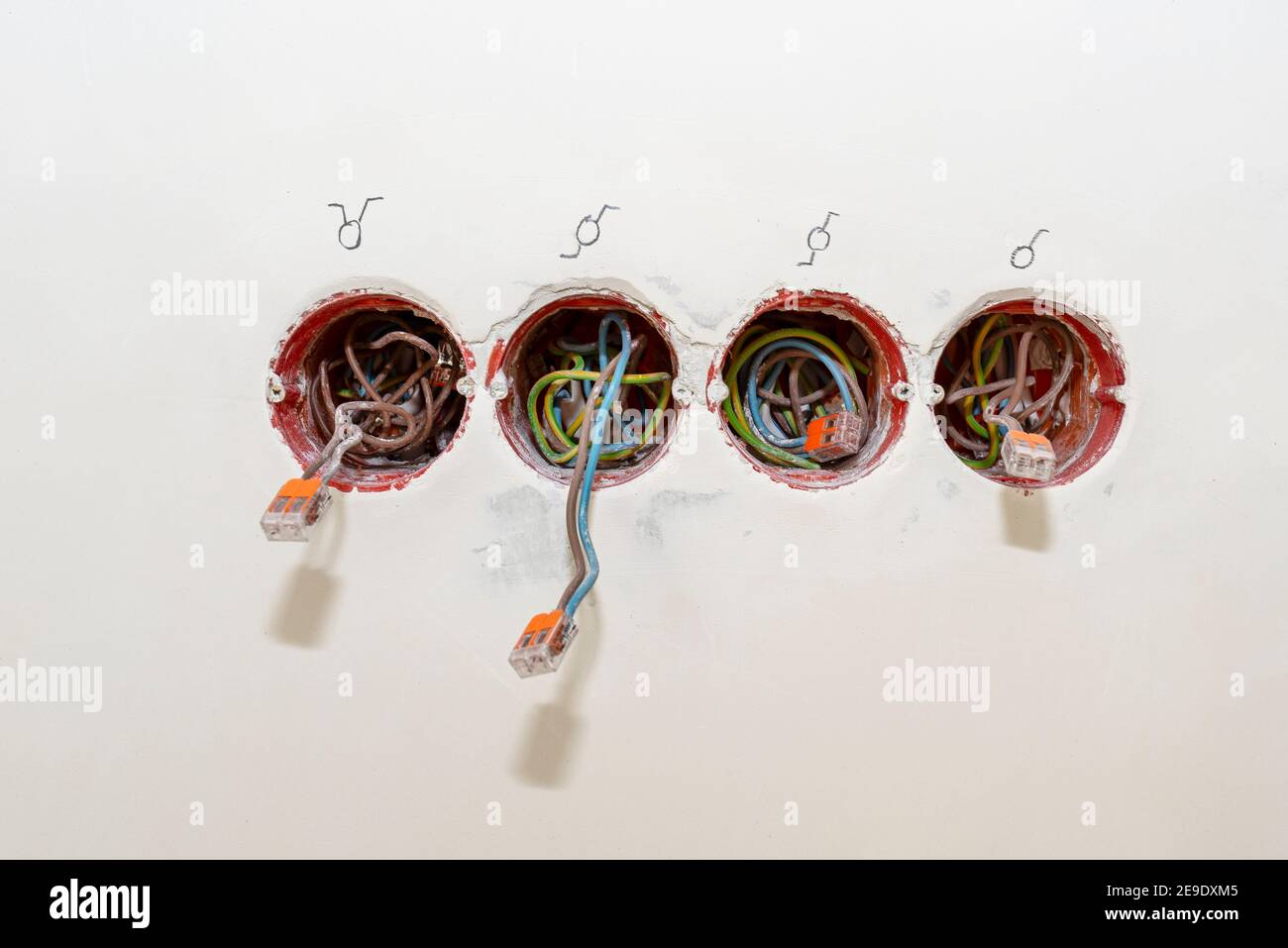 Electric cables sticking out of an orange box placed in the wall of the ...