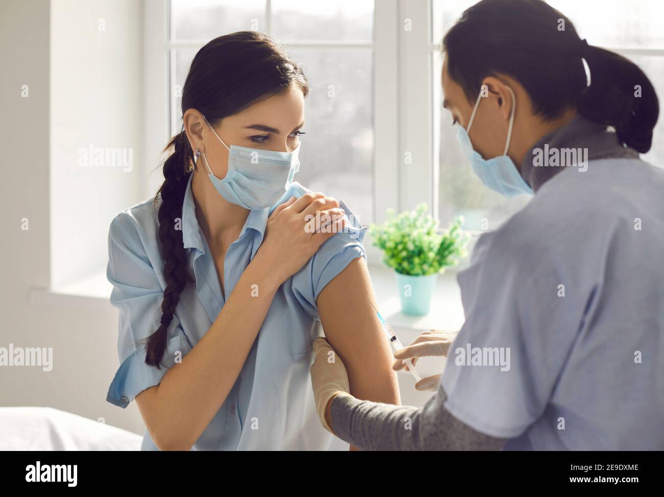 Young woman getting vaccine shot during immunization campaign at clinic ...