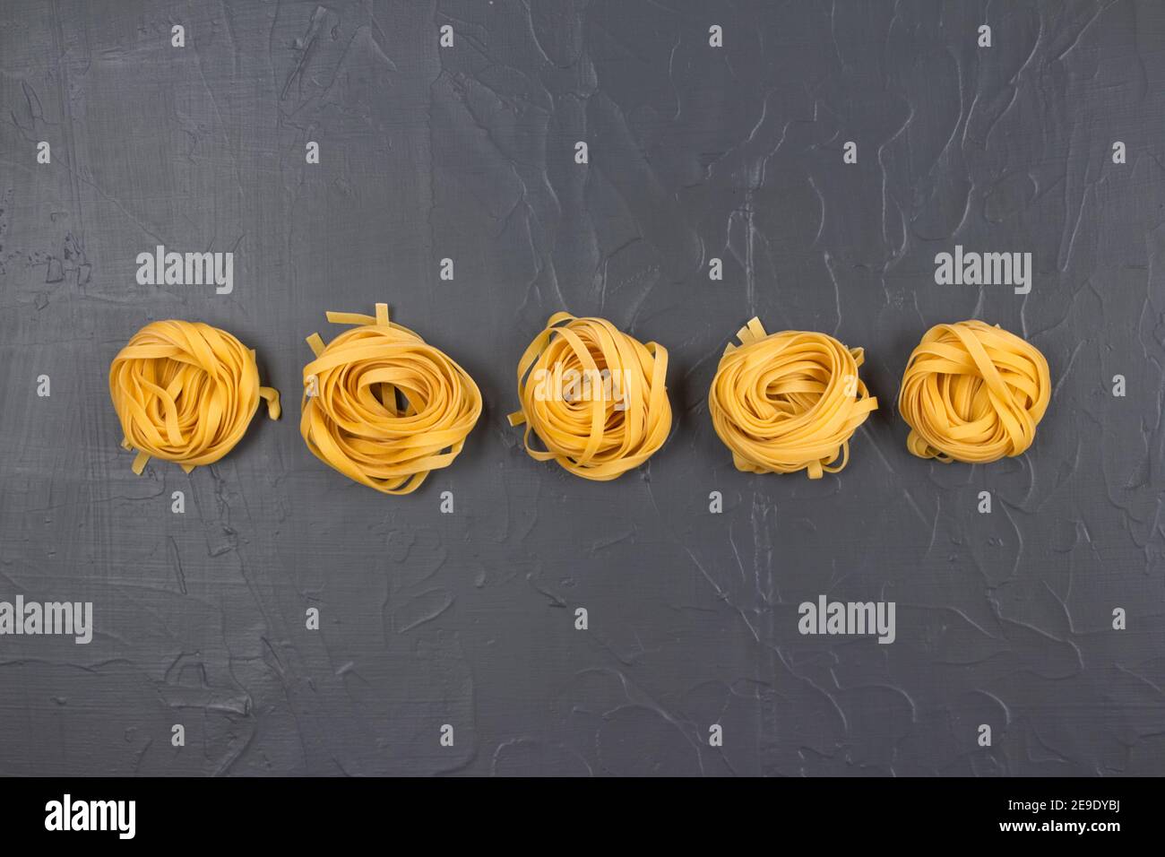 Top view on homemade tagliatelle nests, yellow pasta over gray stone ...