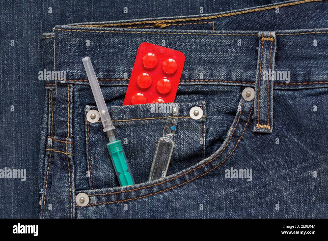 Injection syringe with ampulla and red packaging with pills are lying ...