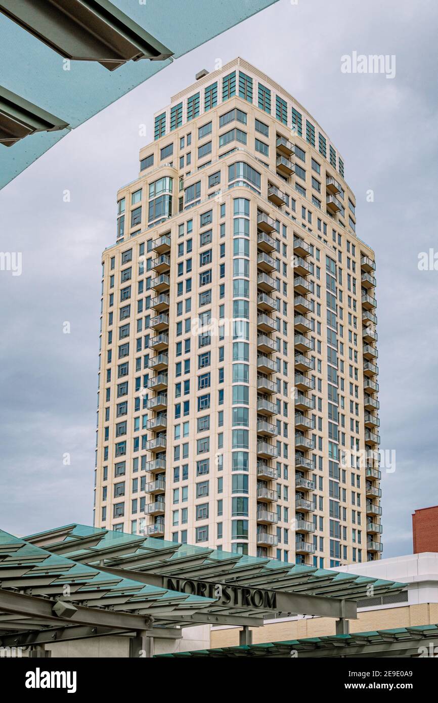 Vertical shot of a concrete high-rise building under a rainy cloudscape ...
