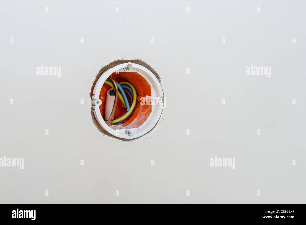 Orange, round installation box mounted in a white wall with an ...