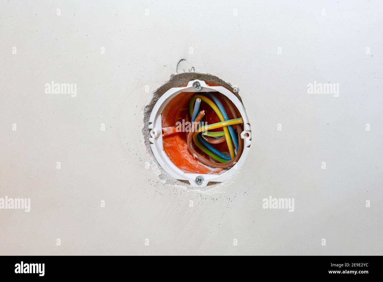Orange, round installation box mounted in a white wall with an ...