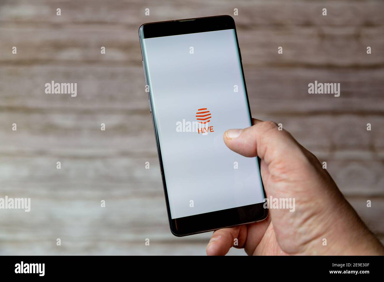 A hand holding a Mobile phone or cell phone with the Hive smart home ...