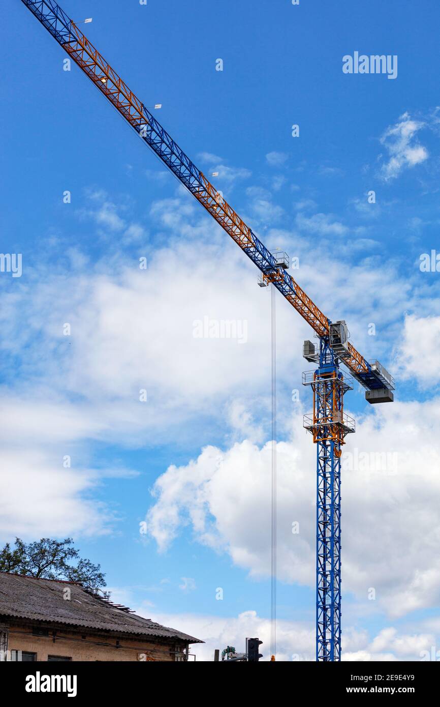 An arrow of a tower crane against a blue sky, divides the image ...