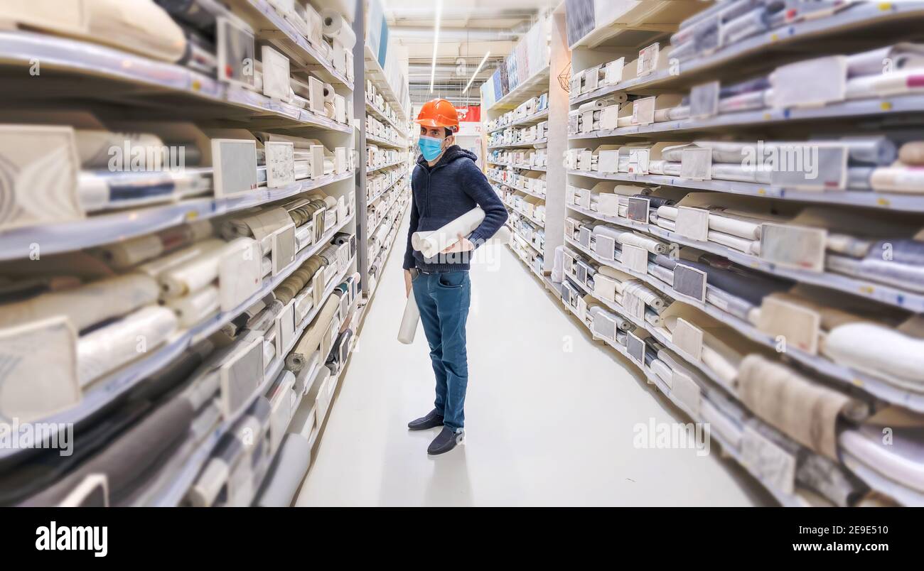 A man in a hardware store. Wallpaper for sale. Selective focus. People ...