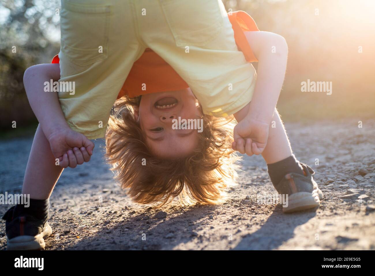 Portraits of happy child playing upside down outdoor in summer or ...