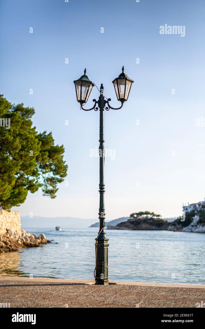 Single street lamp on the pier seafront with flowing water at sunset in ...