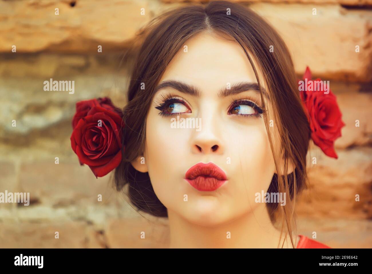Curious woman with red lips and fresh roses in hair Stock Photo - Alamy