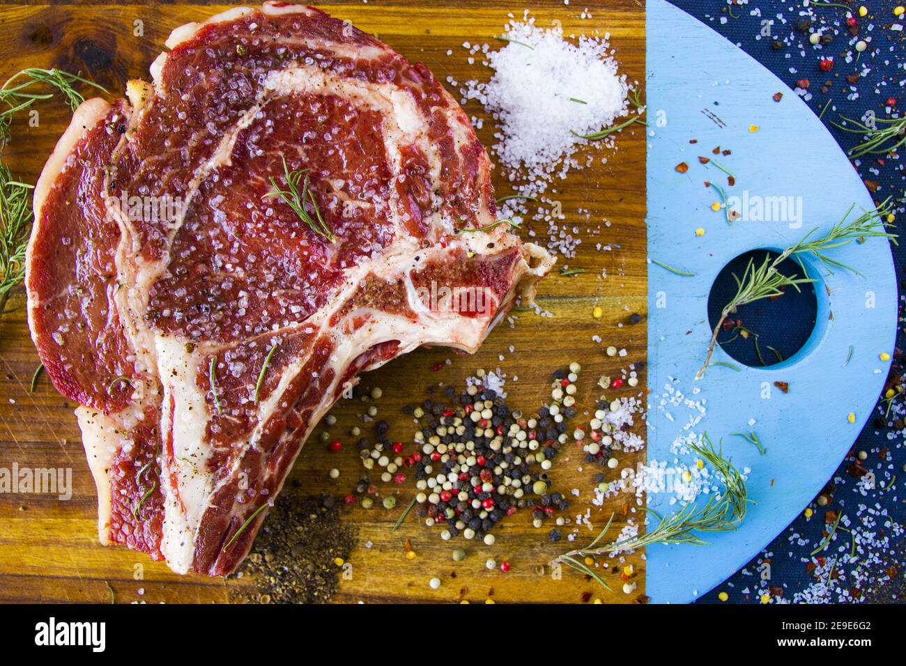 Slice of raw beef meat on the table with rosemary and other spices, rib ...