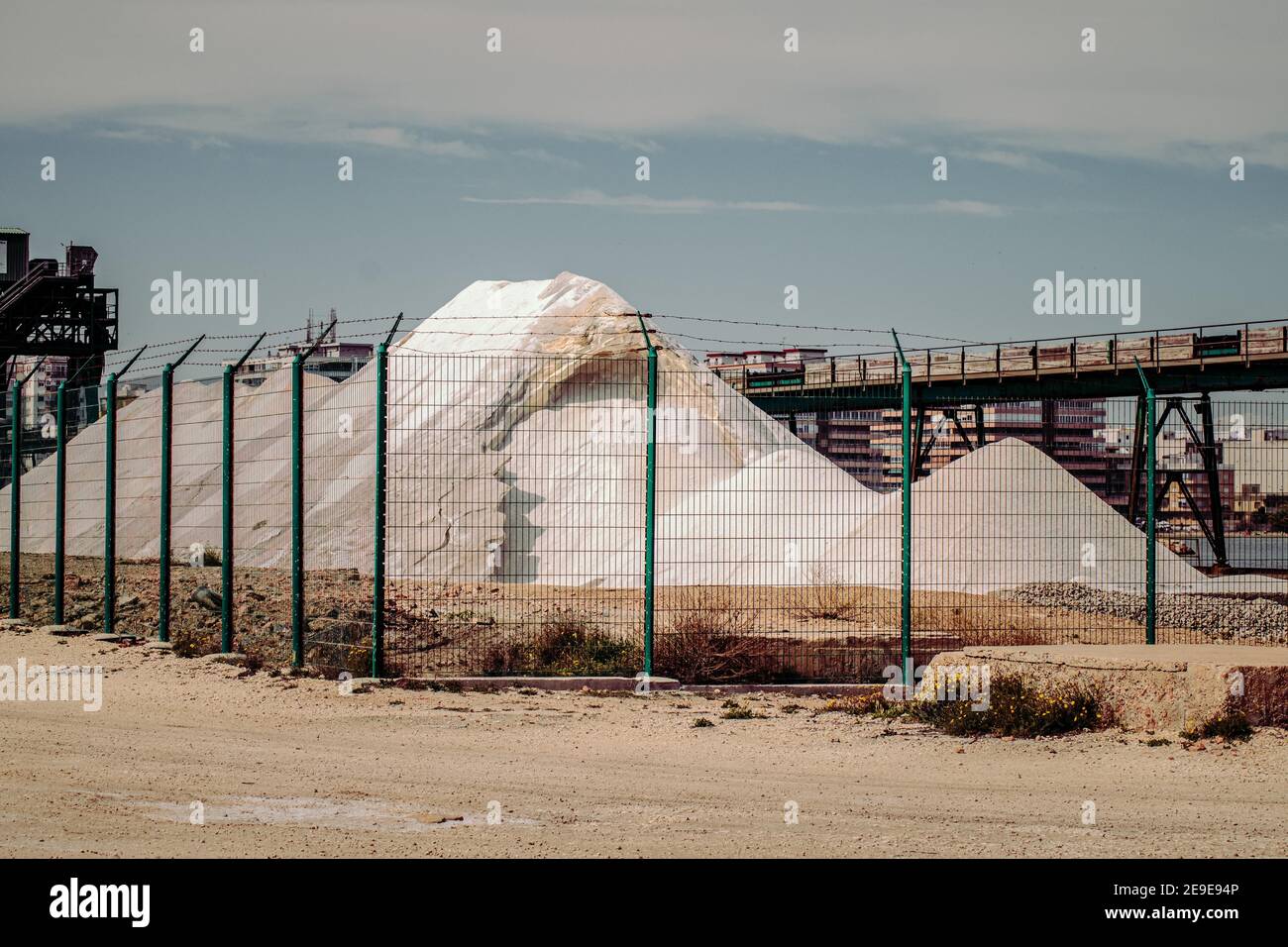 Salt mining factory with salt piles behind a metal fence Stock Photo ...