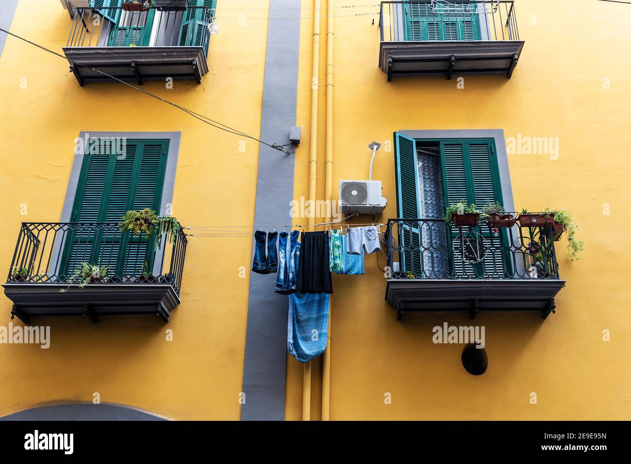 Facade of a yellow classic building with hanging clothes in the ...