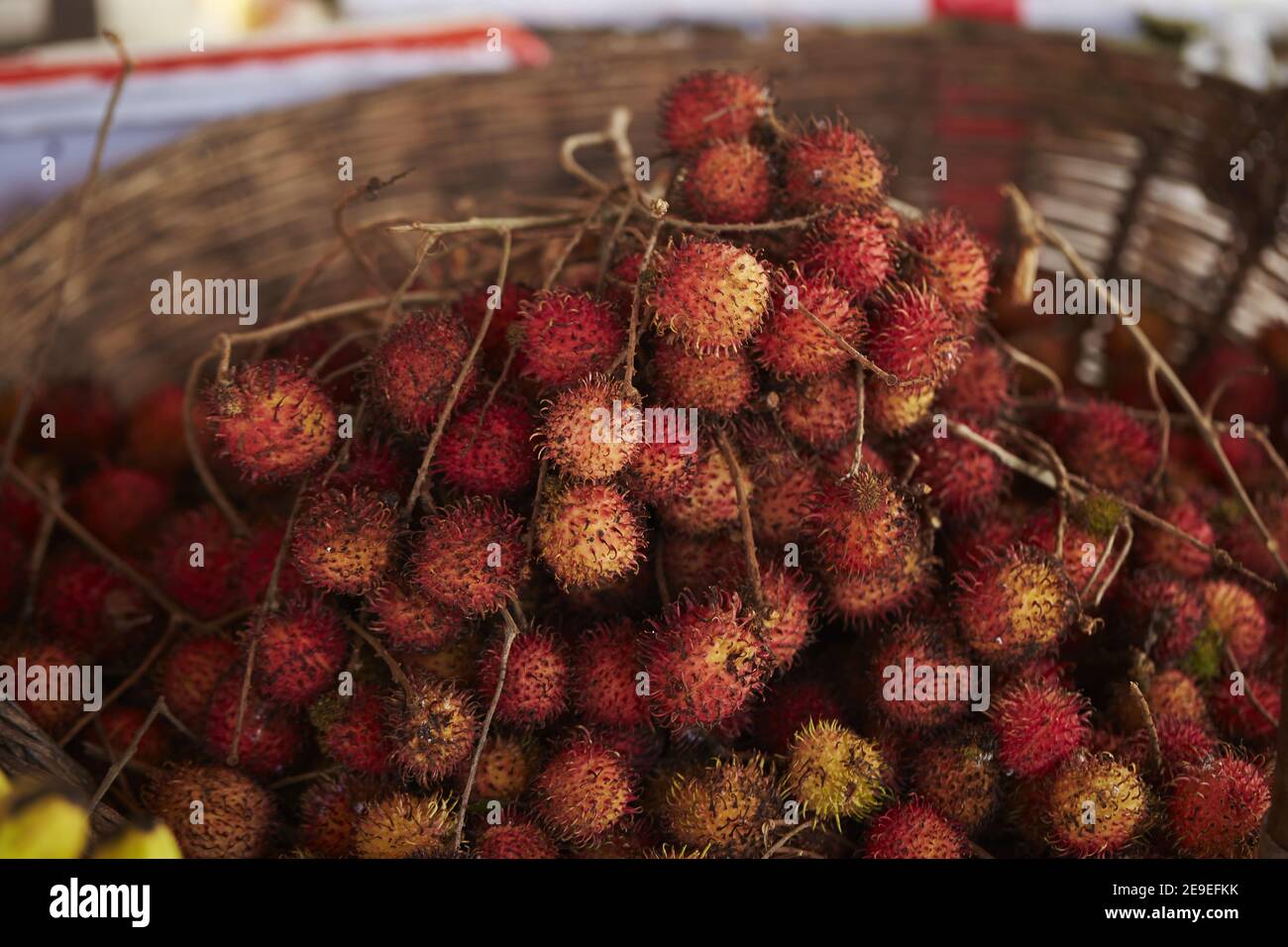 Closeup shot of red rambutan in a basket in a food mark Stock Photo - Alamy
