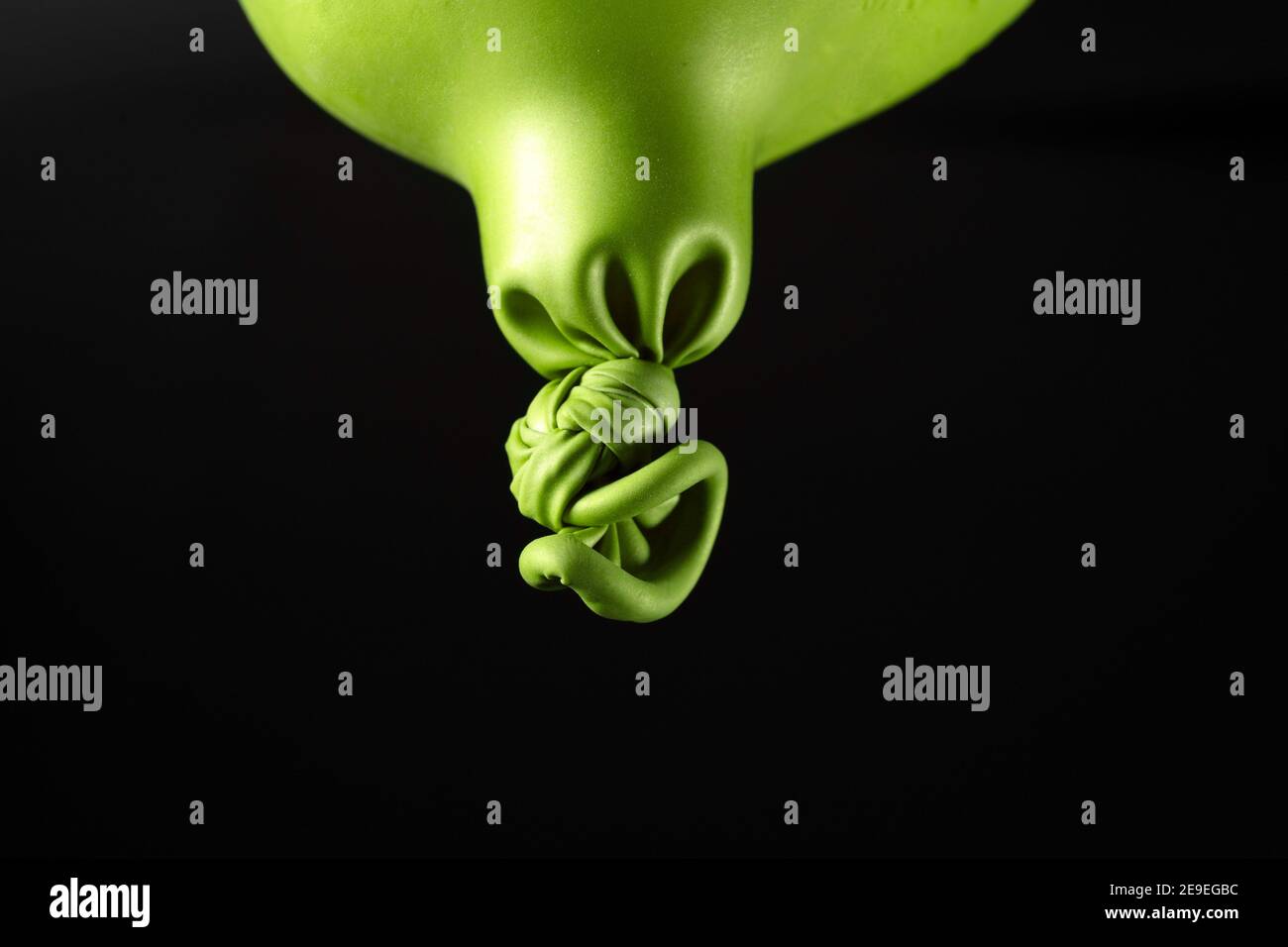 Close-up of a knot of an inflated green balloon with scenic side light ...
