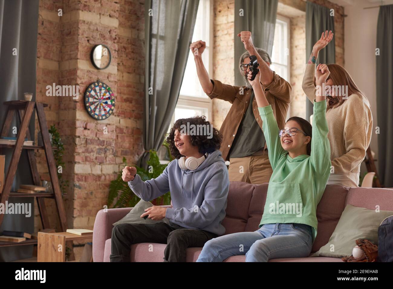 Family of four having fun together during playing video games at home ...