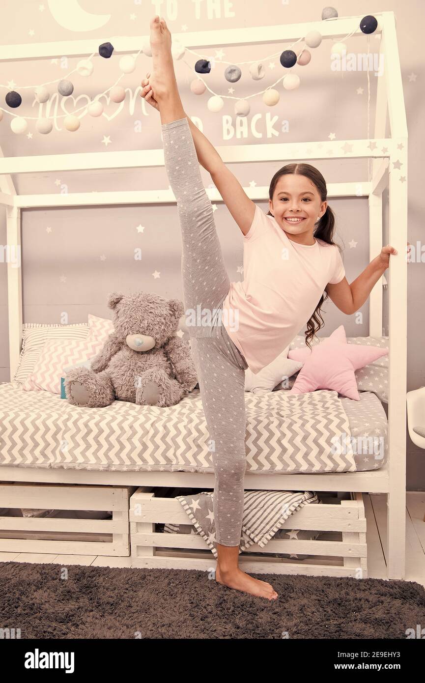 Improve flexibility. Girl child split in bedroom. Kid prepare go to bed ...